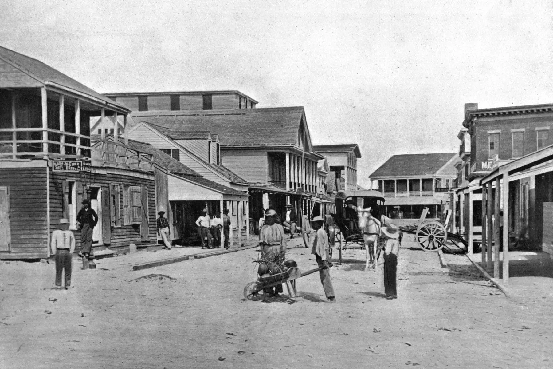 Ulica v Key Westu, Florida, ZDA, okoli leta 1900. Lesene zgradbe in neasfaltirana cesta.