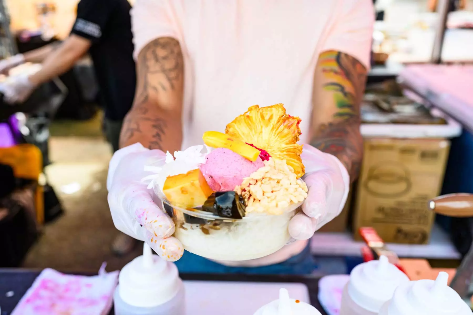 In New York City, USA, zeigt ein arbeitender Lebensmittelverkäufer mit Schutzhandschuhen ein frisch zubereitetes philippinisches Dessert beim Smorgasburg Food Event.