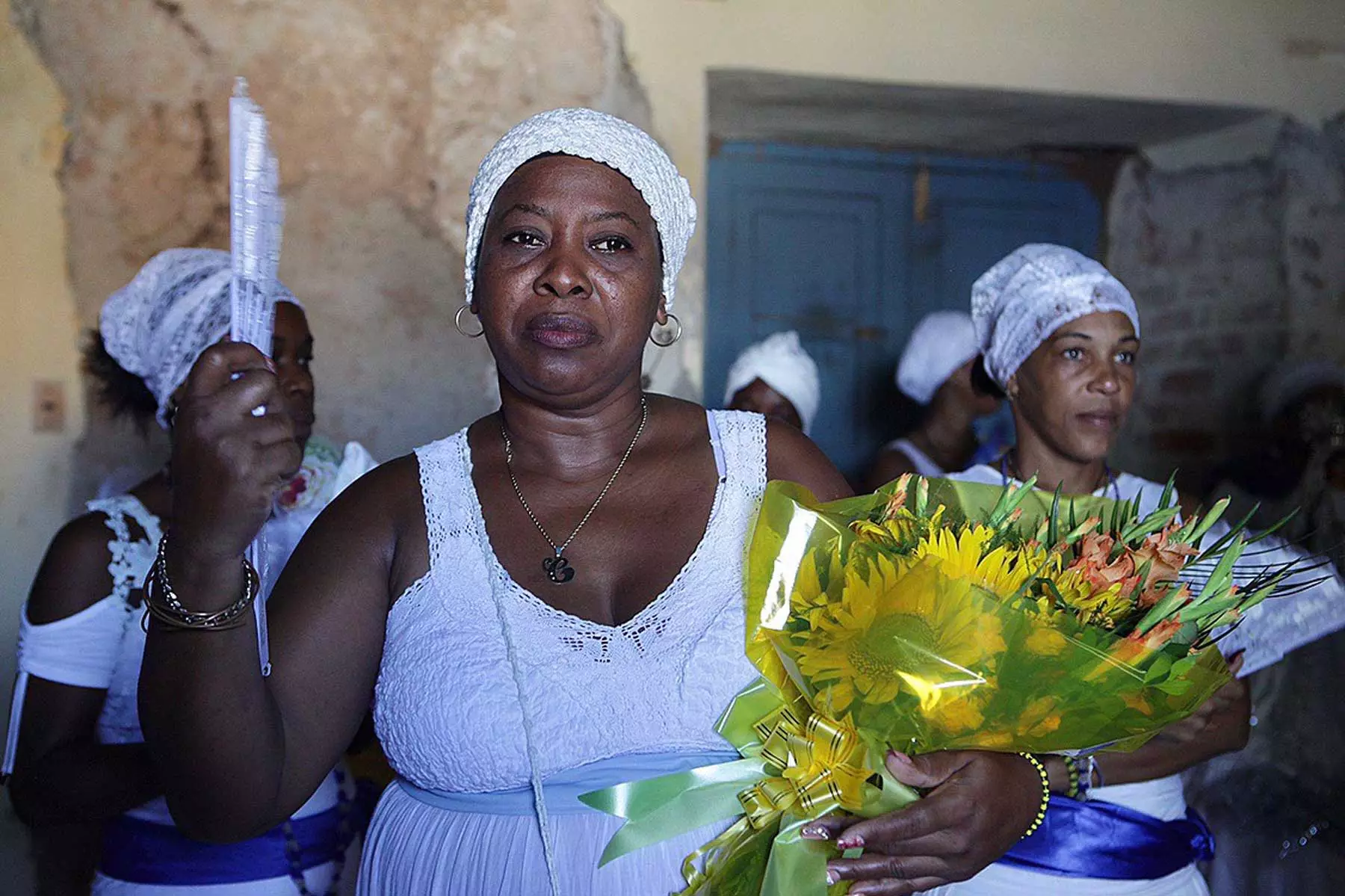 Afro-kubánské ženy v bílých šatech drží květiny