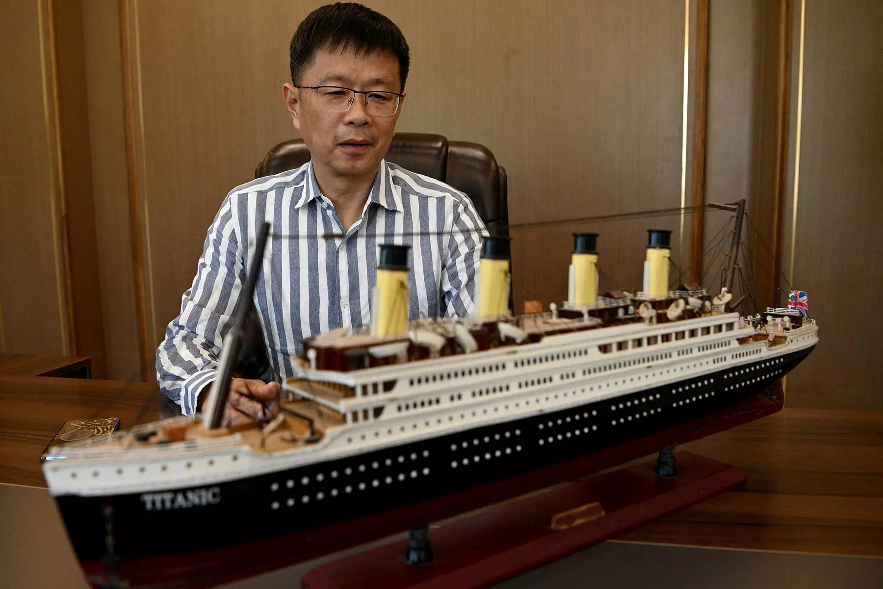 Un investitor care ajută la construirea unei replici în mărime naturală a Titanicului, lângă un model al navei