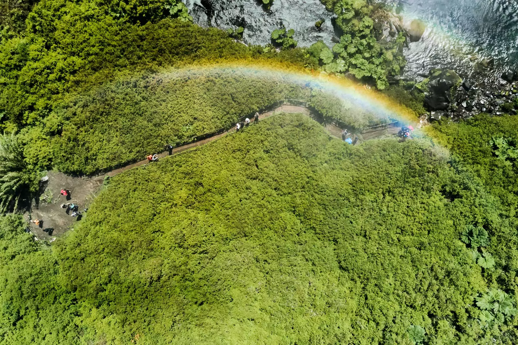 Una veduta aerea di un sentiero che conduce a una cascata vicino a Pucon, in Cile, con un arcobaleno che si estende sulla foto