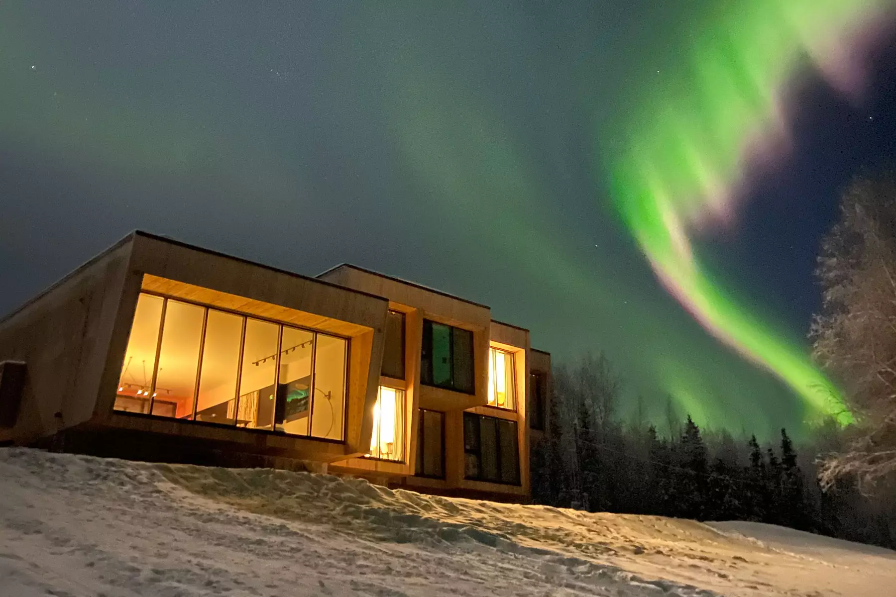 Tampilan njaba Aurora Villa ing Alaska kanthi Lampu Lor sing mencorong ing ndhuwur