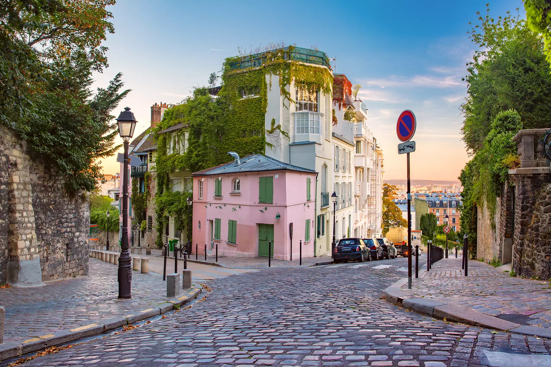 프랑스 파리의 몽마르뜨(Montmartre) 지구, 햇살 가득한 일출에 분홍색 집이 있는 아늑한 옛 거리