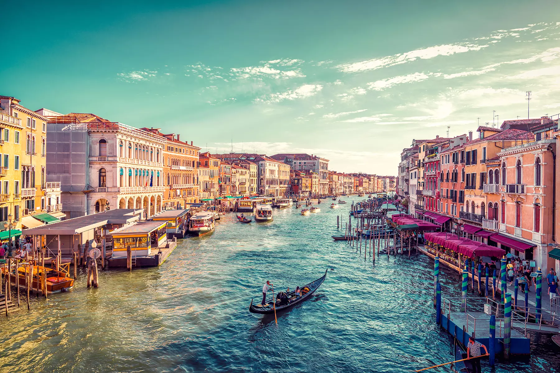 Un gondolero rema hacia la puesta de sol en el Gran Canal de Venecia.