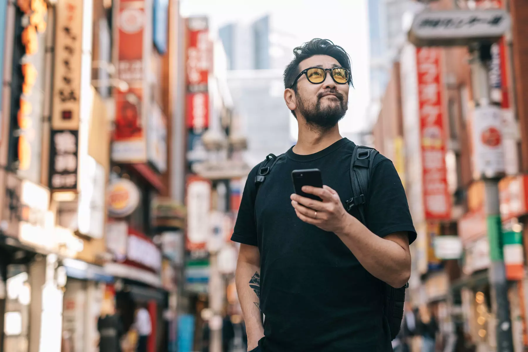 Asiatisk mann som reiser ved hjelp av mobiltelefon