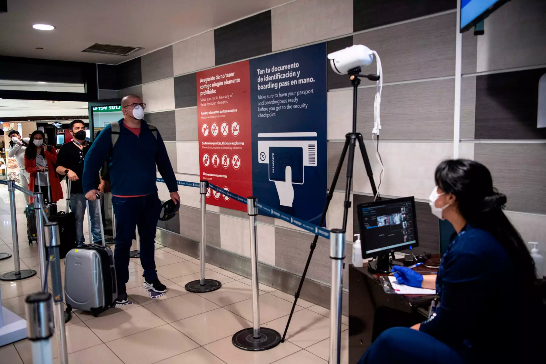 In wurknimmer fan it Ministearje fan Folkssûnens fan Sily kontrolearret in skerm fan in thermyske scanner om de lichemstemperatuer fan in passazjier te kontrolearjen foardat hy oan board fan in flecht op Santiago International Airport