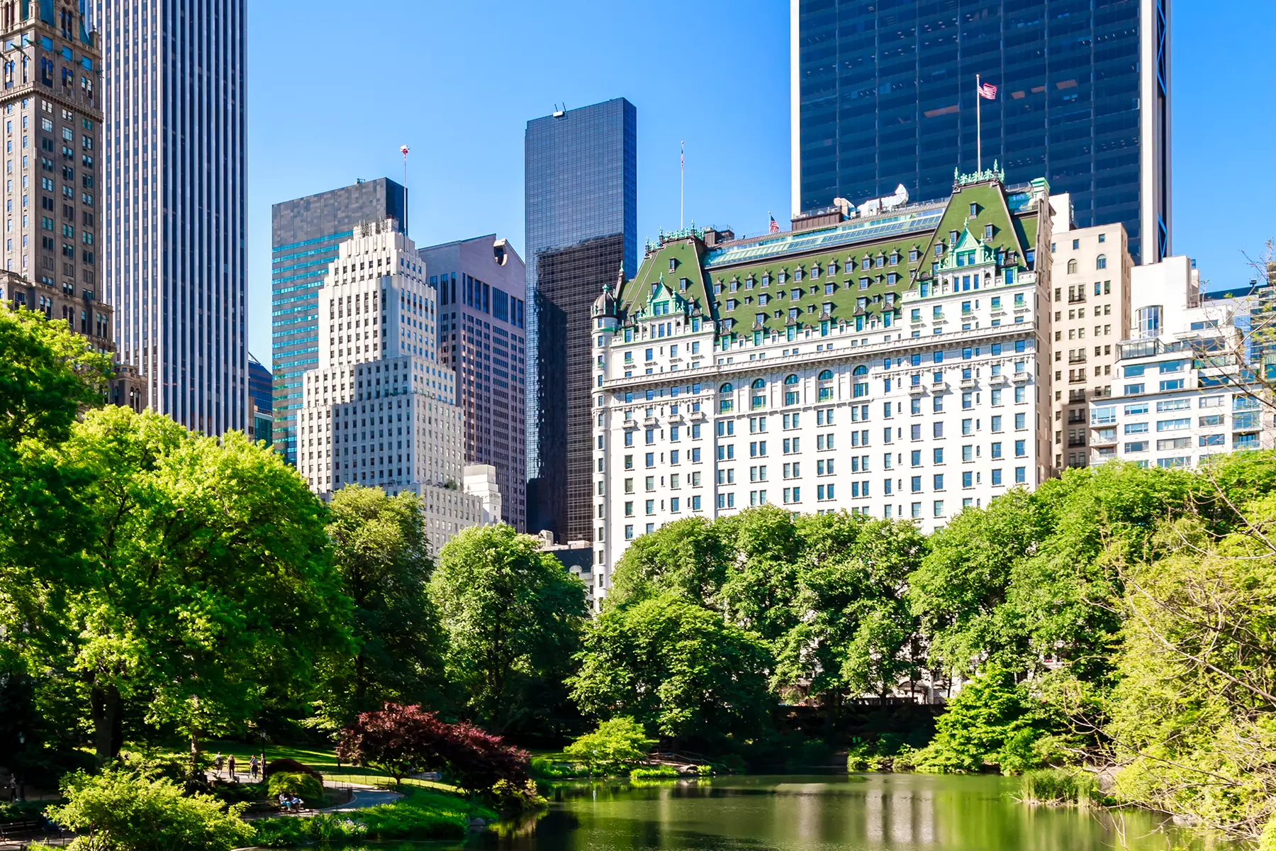 Lo Skyline di Midtown Manhattan si erge sopra il Central Park nel suo angolo sud-est in alto in un cielo azzurro.