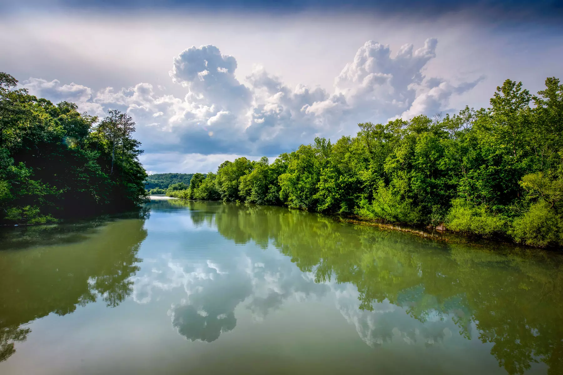 Arroyo de verano y paisaje con nubes que se reflejan en el agua