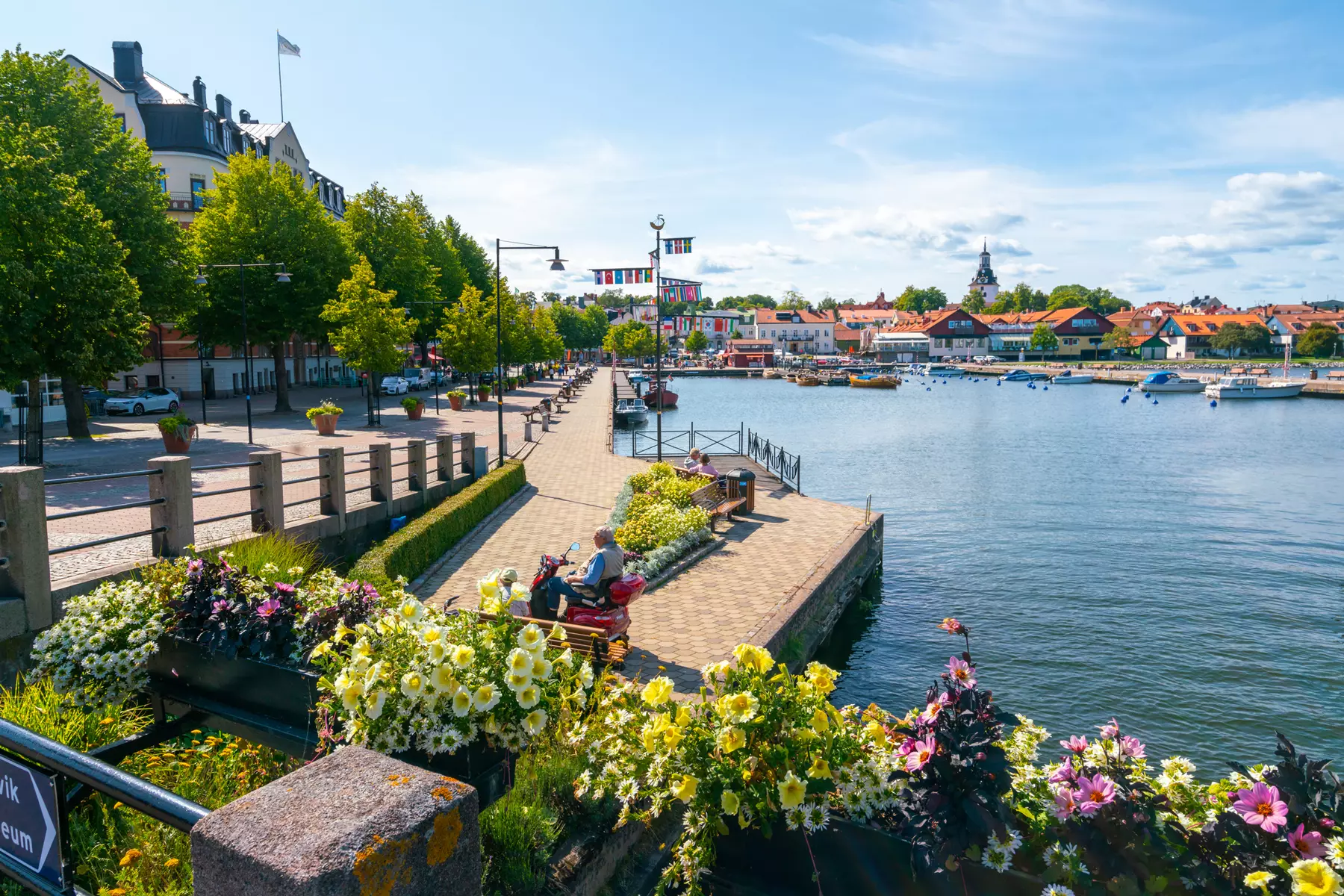 Cityscape ta 'Vastervik bit-torri tal-Knisja fuq l-orizzont u bajja tal-belt fuq quddiem. Jum xemxija tas-sajf fin-Nofsinhar tal-Iżvezja