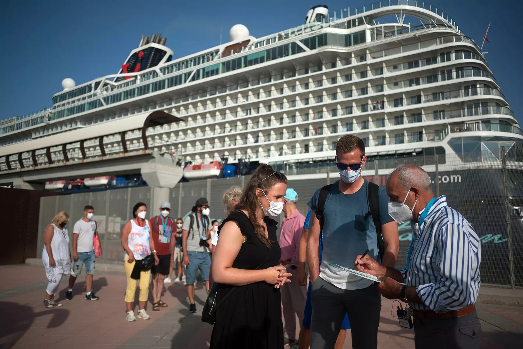 Turister i kø, der venter på at komme ind i en turistbus efter at være gået fra krydstogtskibet.