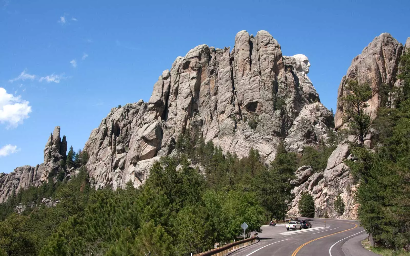 Errepide bihurgunetsu batek Hego Dakotako (AEB) Black Hills-eko Rushmore mendiko harkaitz-azalean landutako George Washingtonen buru zizelkatuaren ondotik pasatzen da.