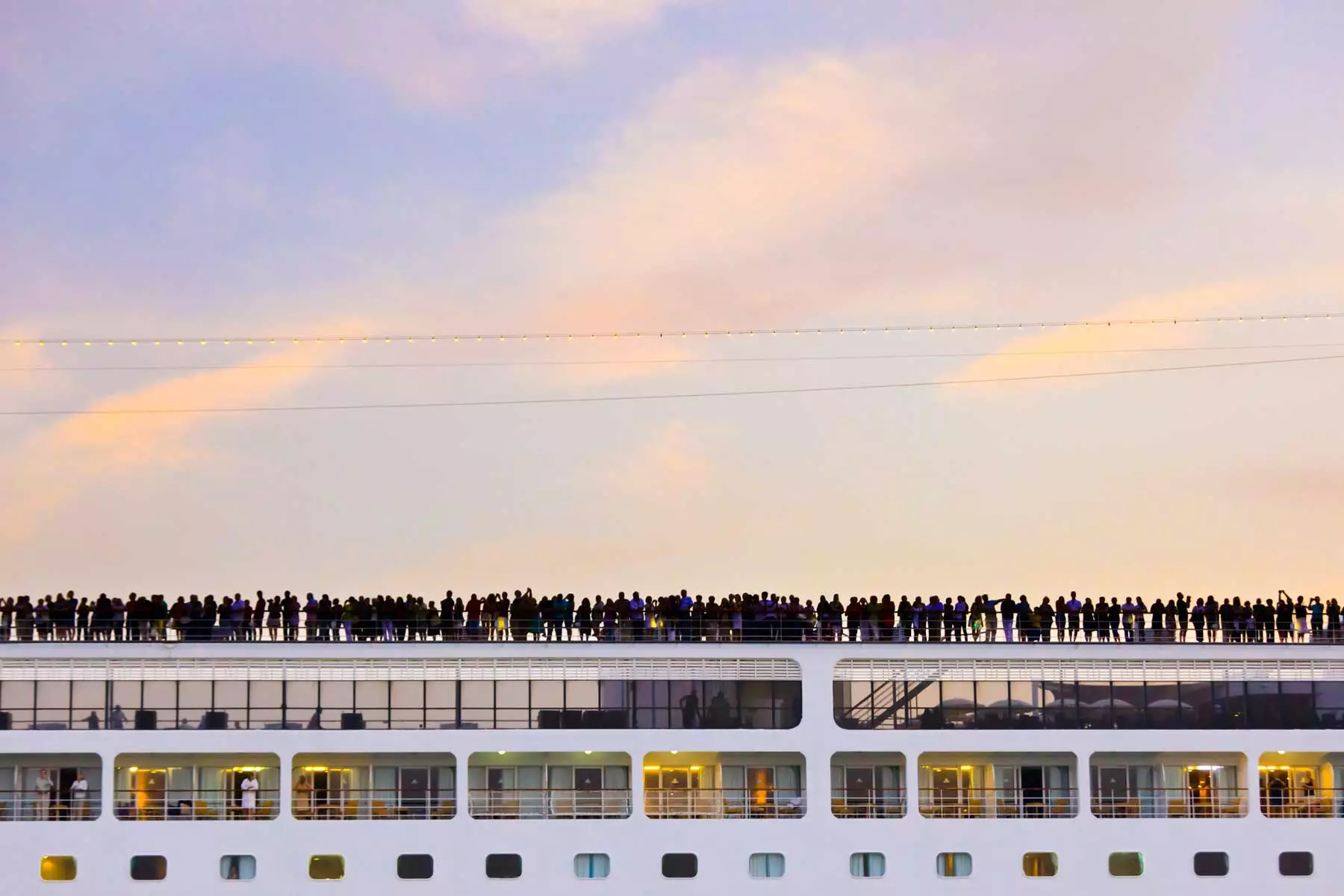 Passagéier op den Top Deck vun engem Croisièreschëff bei Sonnenënnergang