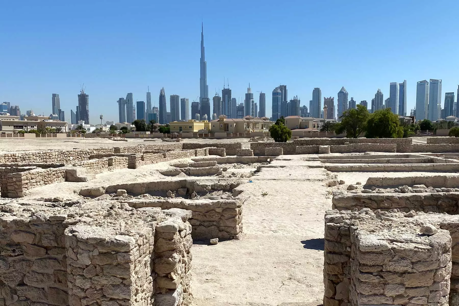 Die oorblyfsels van 'n negende-eeuse stad by die Jumeirah Argeologiese Terrein, met die Dubai-skyline daarbuite