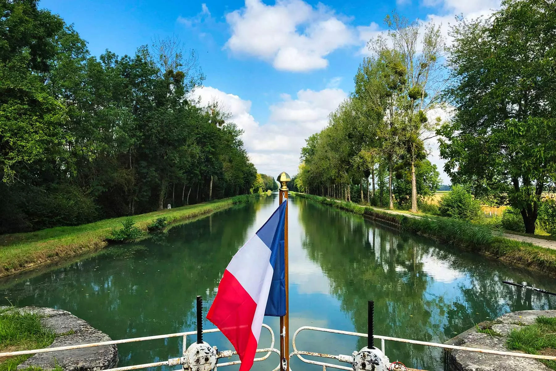 A francia zászló egy hajón, amint áthalad egy zsilipen Brazey-en-Plaine közelében, Franciaország