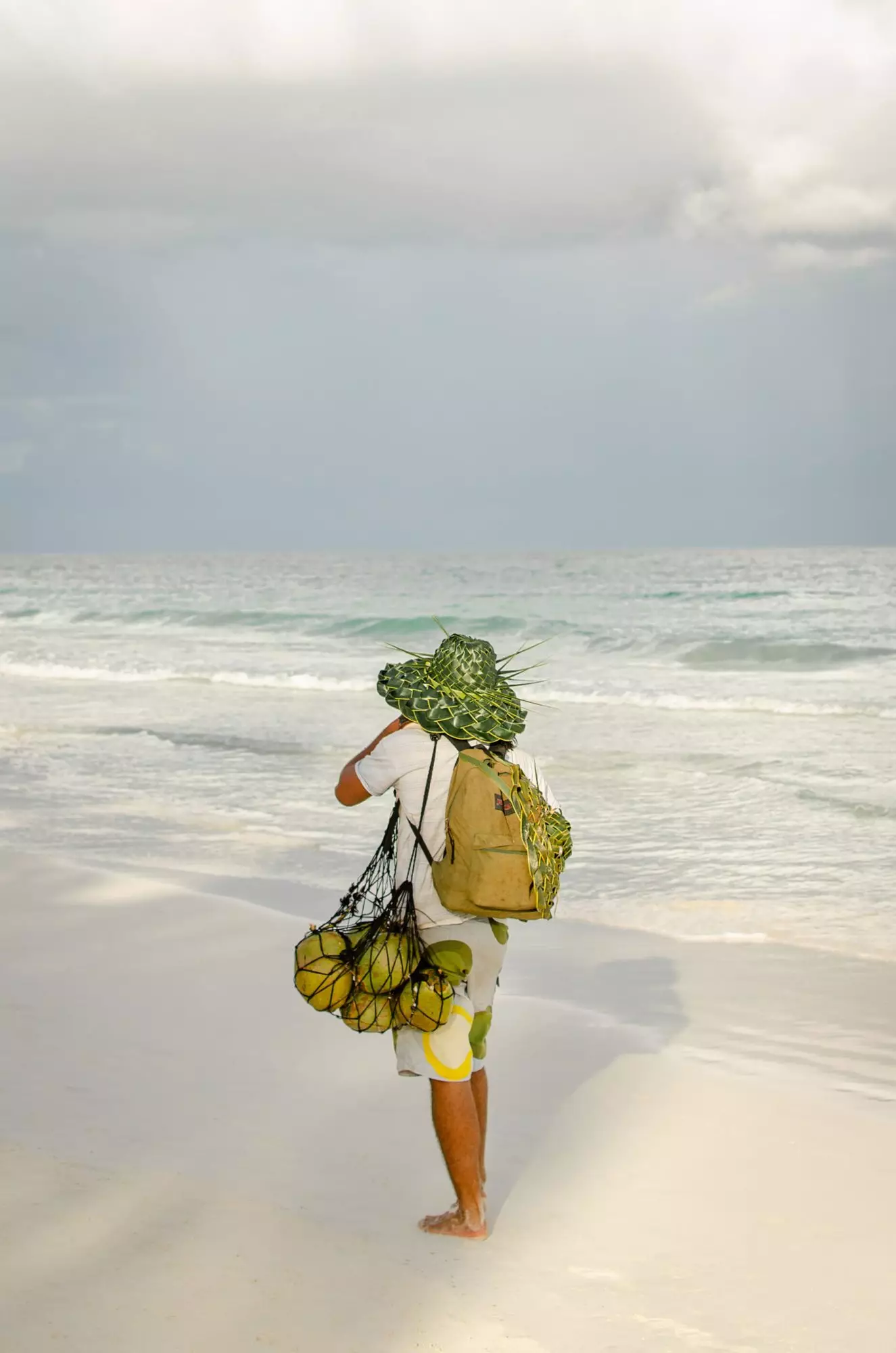 Persoun mat enger Täsch Kokosnëss op der Plage zu Tulum