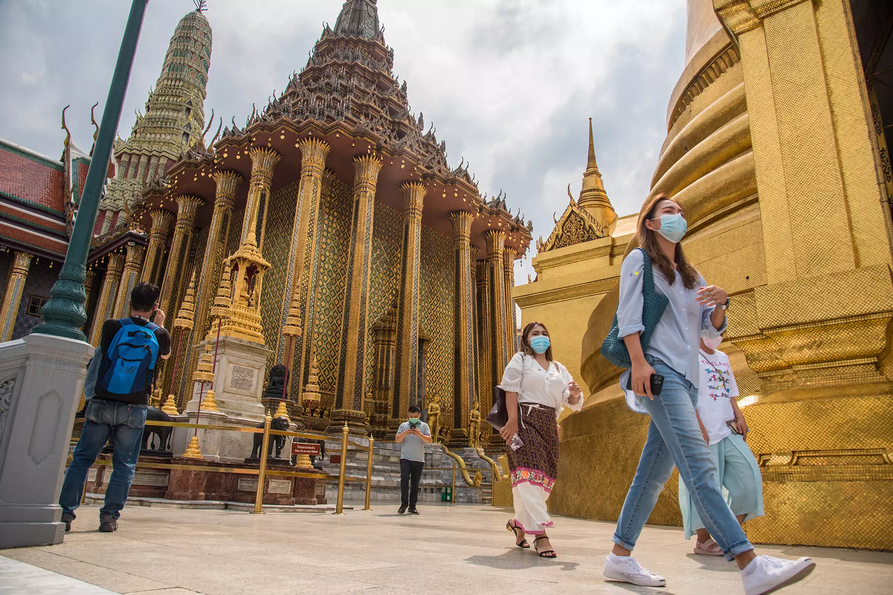 I turisti che indossano maschere per il viso visitano il Grand Palace.