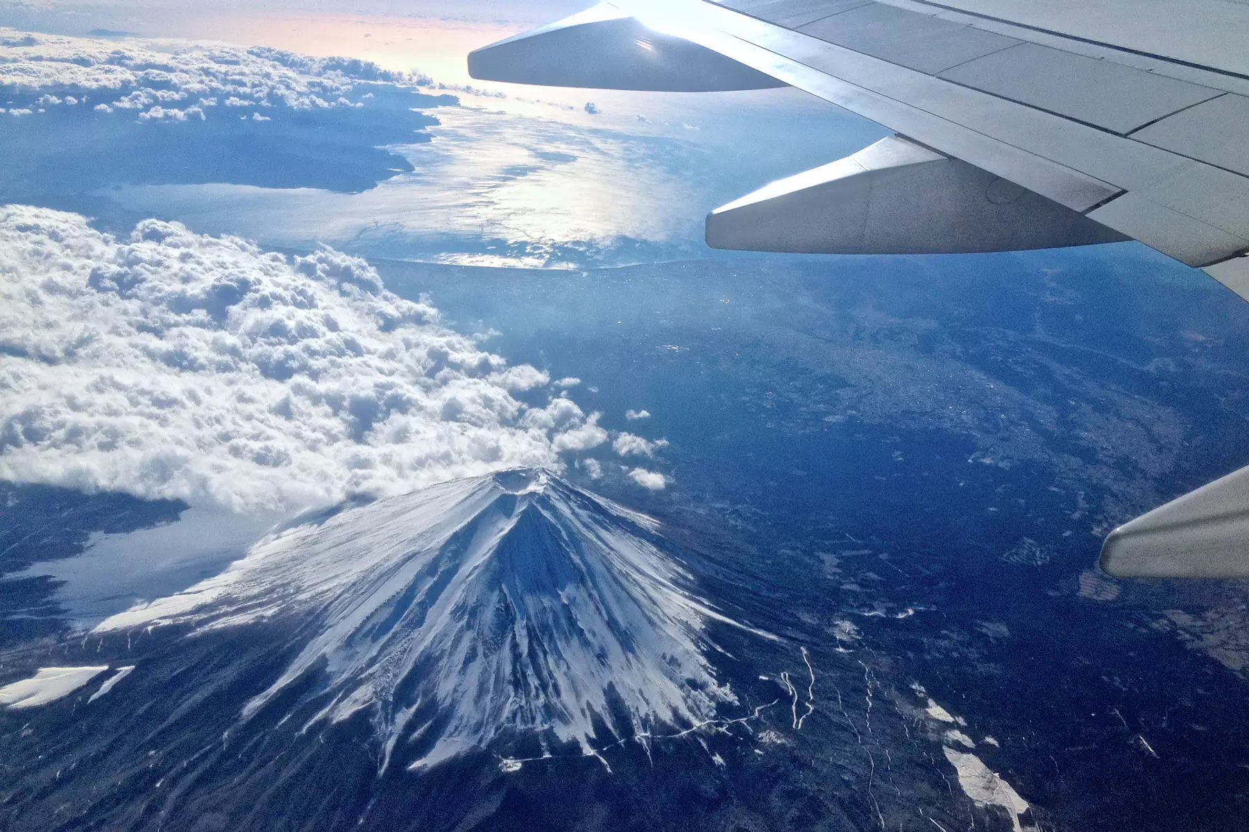 Vista do Monte Fuji cuberto de neve desde un avión voando cunha á ao lonxe da xanela