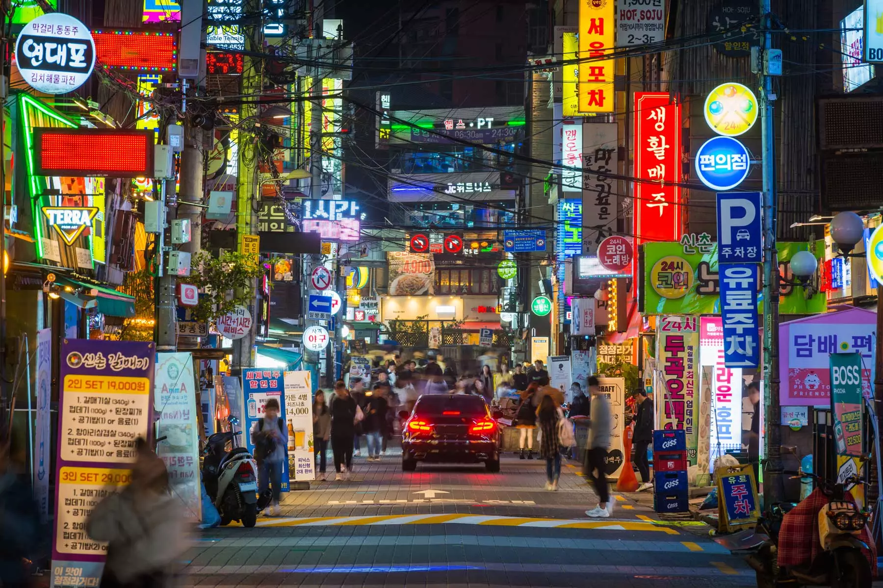 Abantu kwizitrato ezixineneyo ze-neon ebusuku zaseSinchon kumbindi weSeoul, idolophu elikomkhulu laseMzantsi Korea.