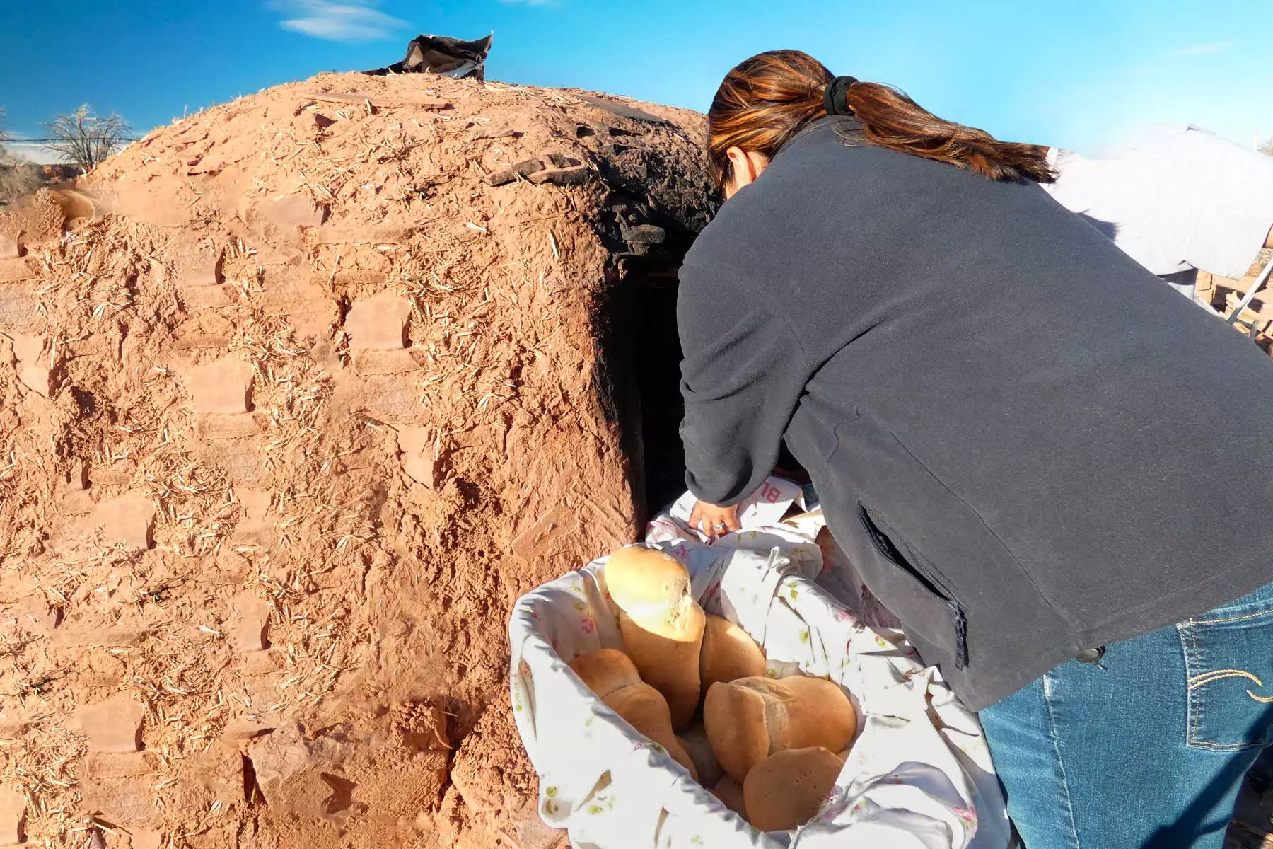 Uma mulher fazendo pão tradicional Zuni em um forno feito da terra