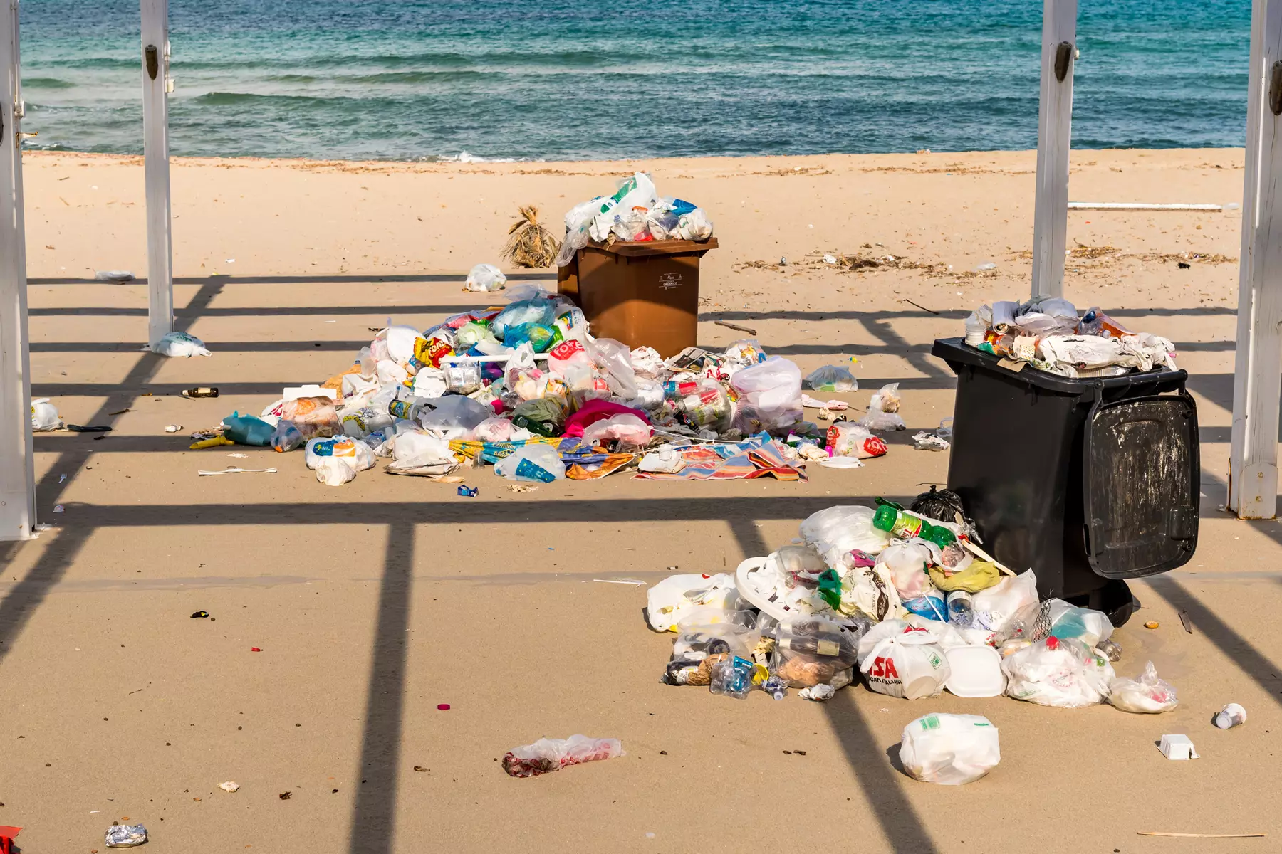 Recipientes com lixo na areia na Isola delle Femmine na Sicília.