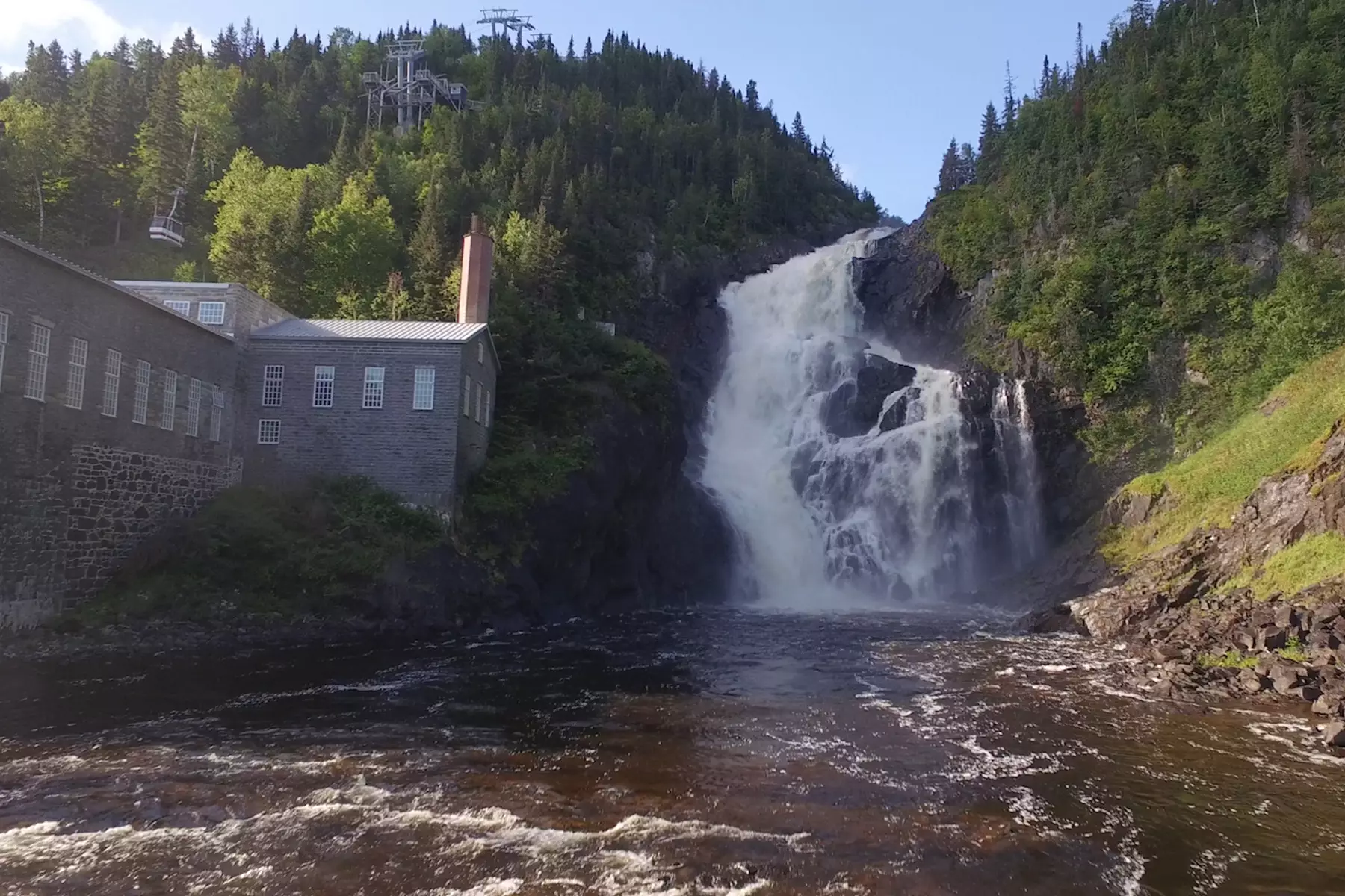 Adeilad wrth ymyl rhaeadr yn Val-Jalbert