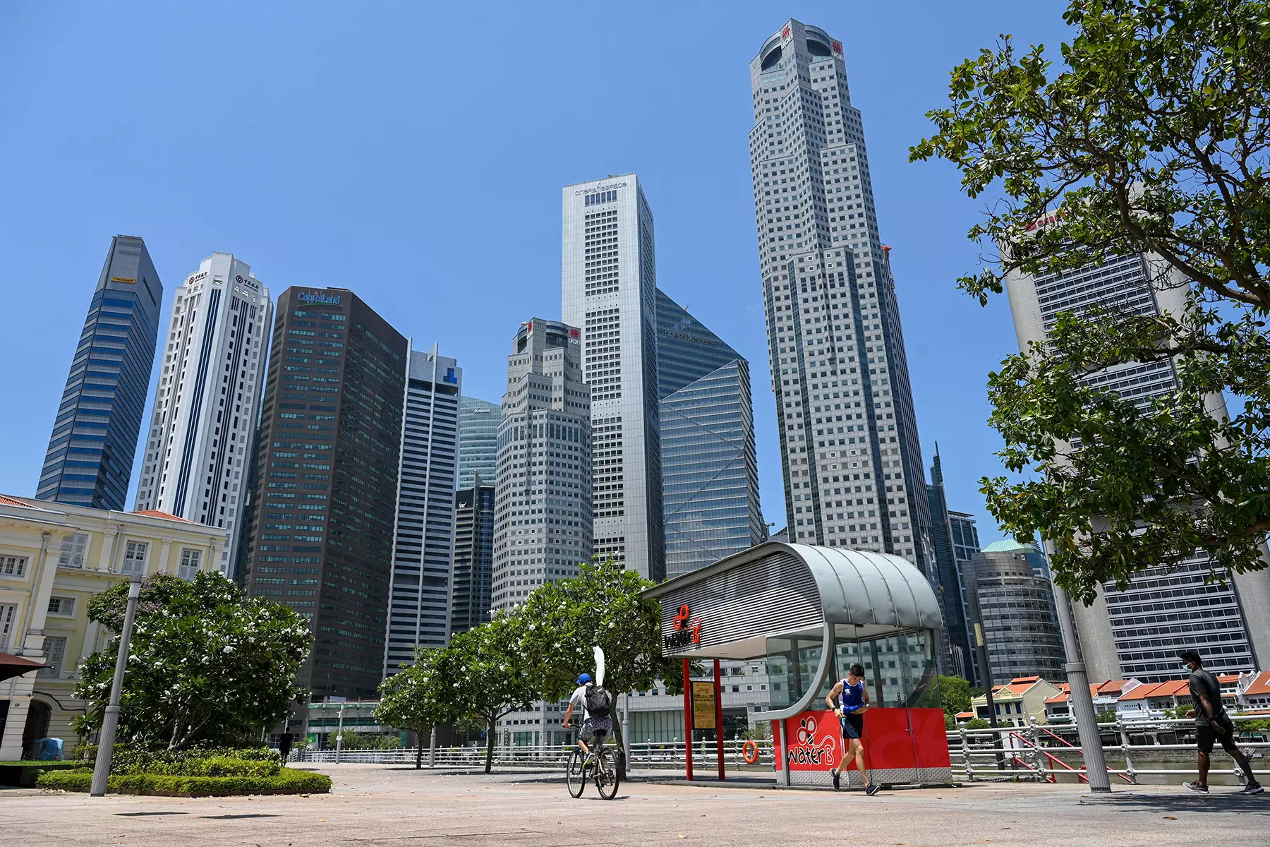 Ludzie przechodzą wzdłuż nabrzeża rzeki w finansowej dzielnicy biznesowej w Singapurze