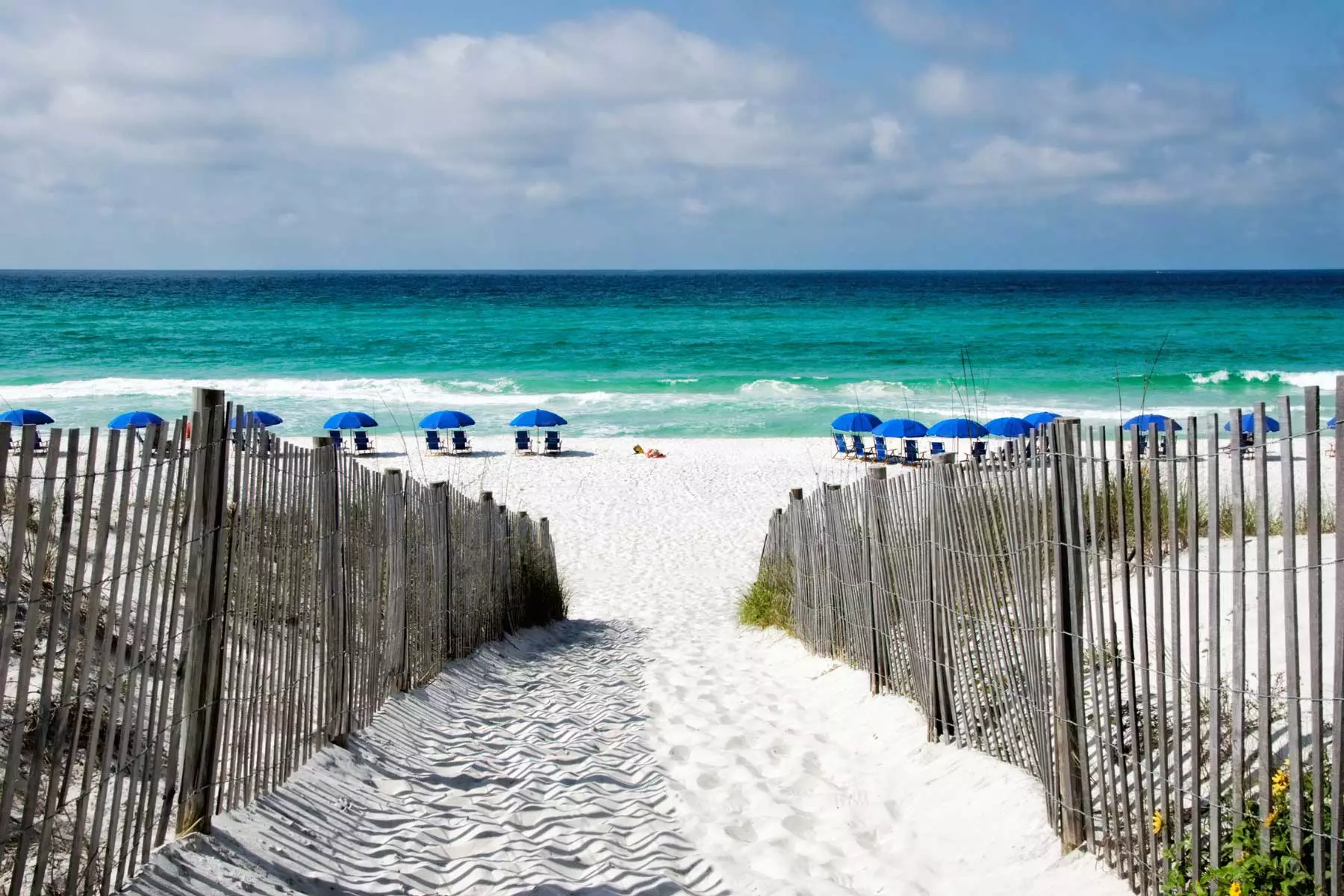 Wit zandvoetpad dat leidt naar een strand bij Seaside Florida in Walton County. De panhandle van Florida staat bekend als de Emerald Coast vanwege de smaragdgroene kleur van het water.