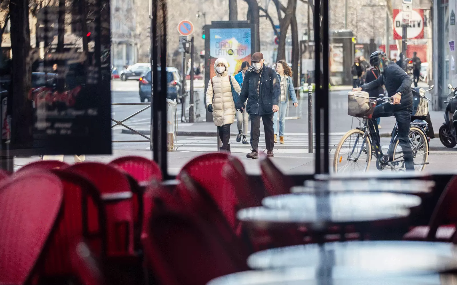 Ljudi koji nose zaštitne maske šetaju ispred zatvorenog restorana