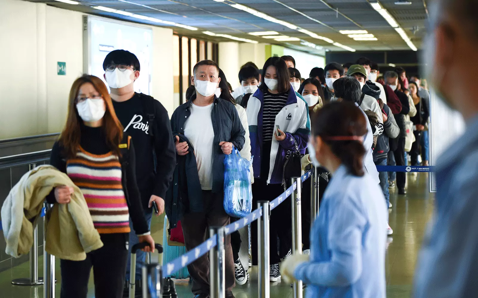 Wisatawan ngagem topéng di Bandara Don Mueang, di Bangkok, Thailand.