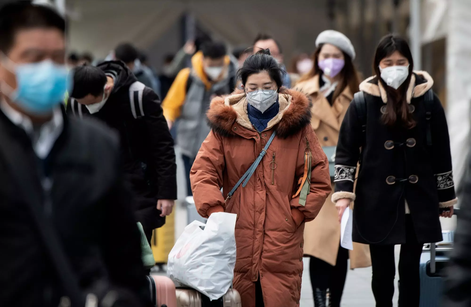 Jalma-jalma anu nganggo topéng pameunteu pelindung sumping ka stasion karéta api di Shanghai.