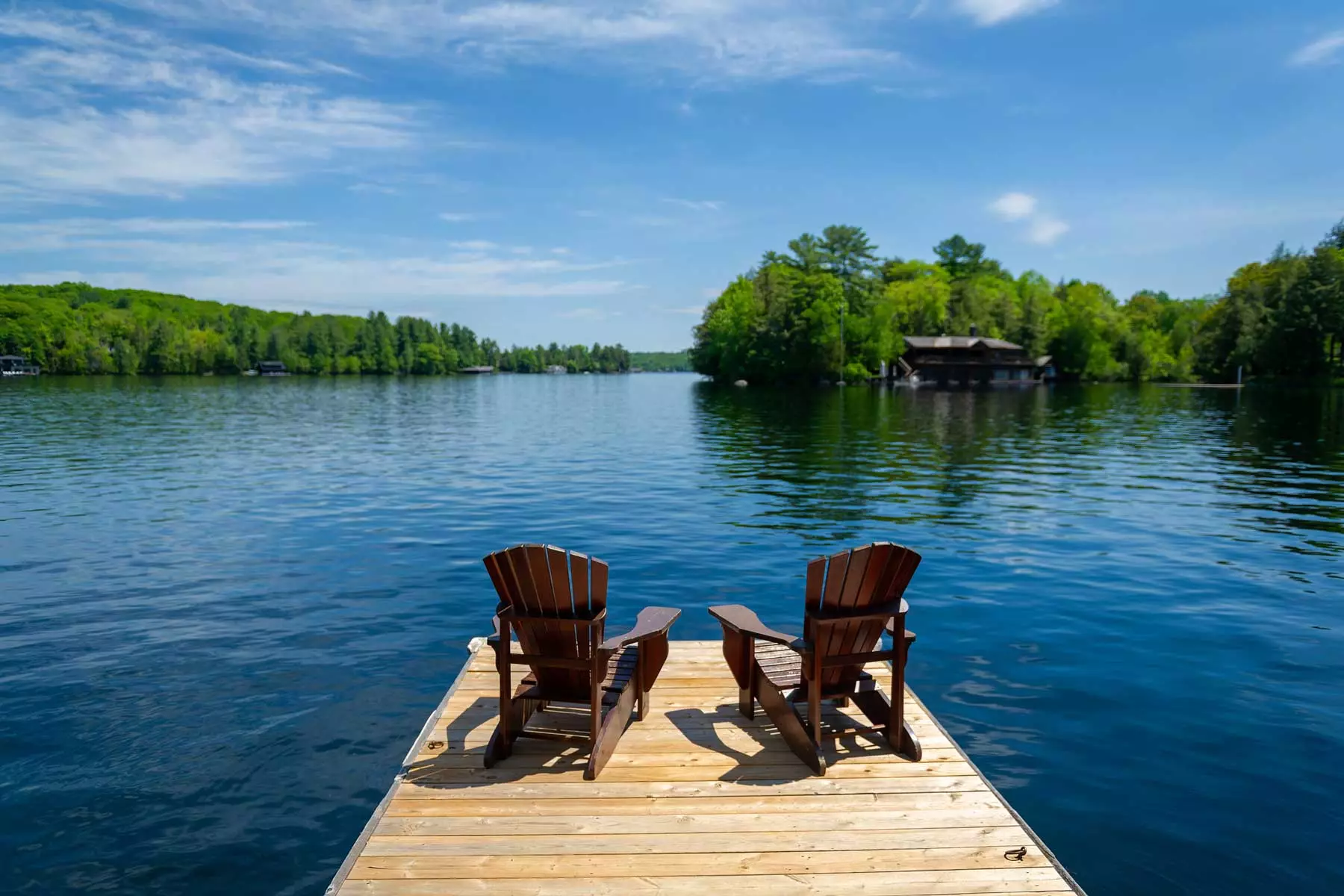 Sedie Adirondack vuote sedute su un molo vicino a un lago