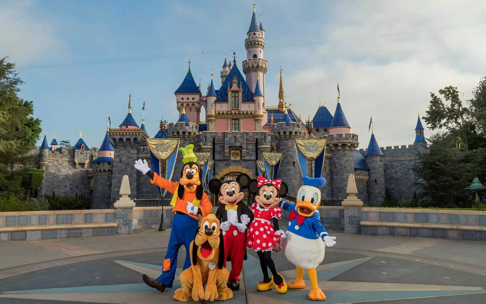 Die Disney-Figuren Goofy, Pluto, Mickey, Minnie und Donald Duck vor dem Schloss im Disneyland in Kalifornien