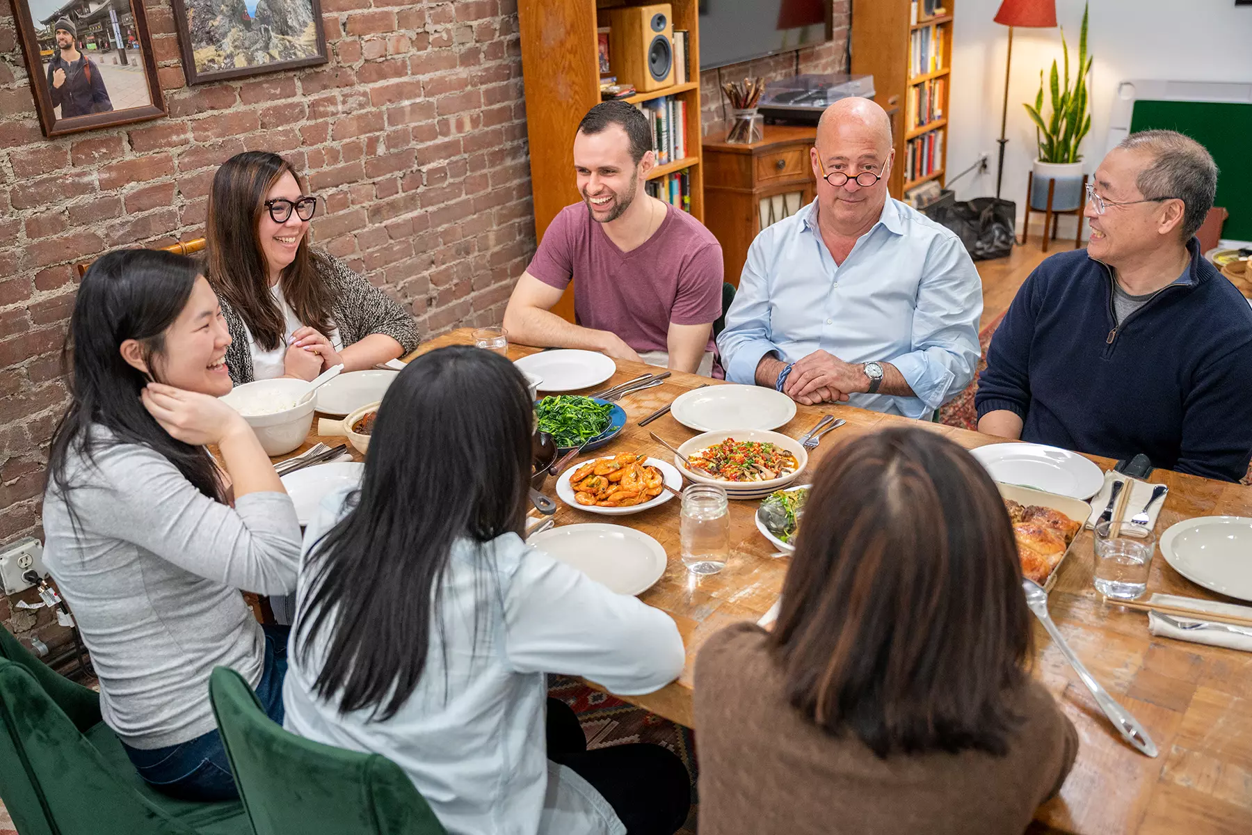 Værten Andrew Zimmern og Leung-familien nyder deres dumplings, ristet kylling med klæbrig ris, Shanghai svinemave, sprød fyldt lotusrod med svinekød, dampet kantonesisk fisk, dine bao-rejer og stegte grønne grøntsager, som det kan ses på Family Dinner, sæson 1 .