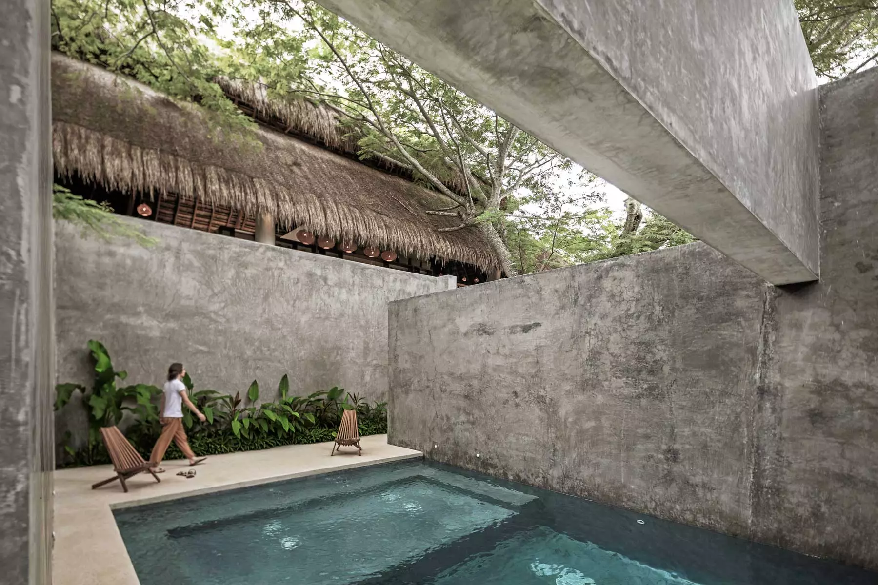 Uma mulher passando por uma piscina no hotel Casa Hormiga, no México