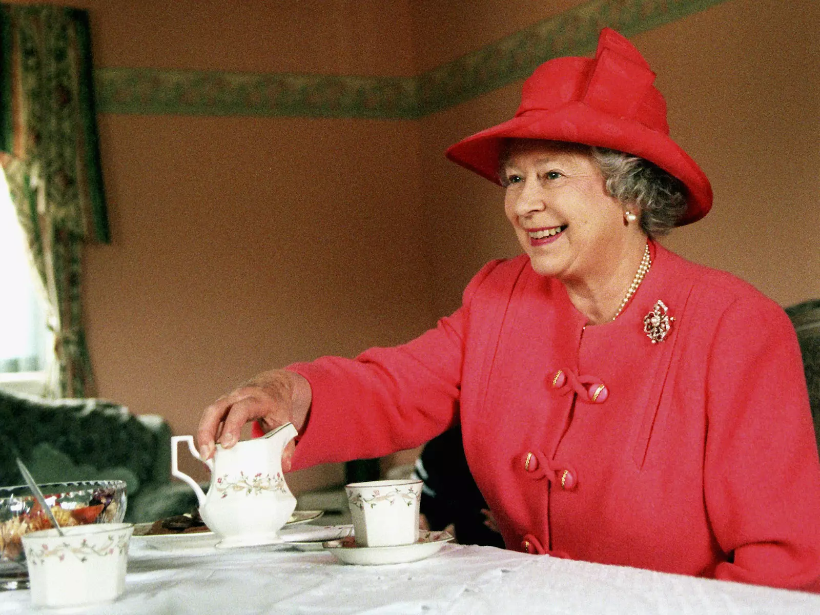 Dronning Elizabeth II blir med fru Susan McCarron, hennes ti år gamle sønn, James, og boligsjef Liz McGinniss på te i hjemmet deres i Castlemilk-området i Glasgow i Skottland 7. juli 1999.