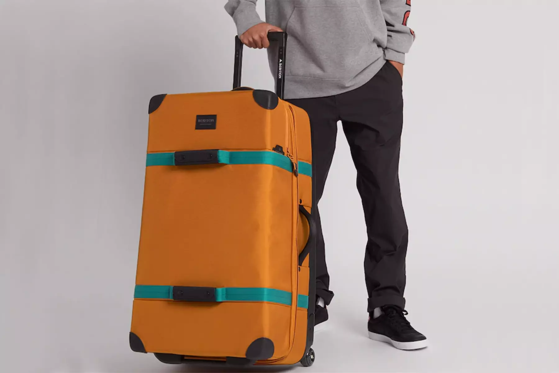 Un uomo con la borsa da viaggio Burton Wheelie Sub 116L