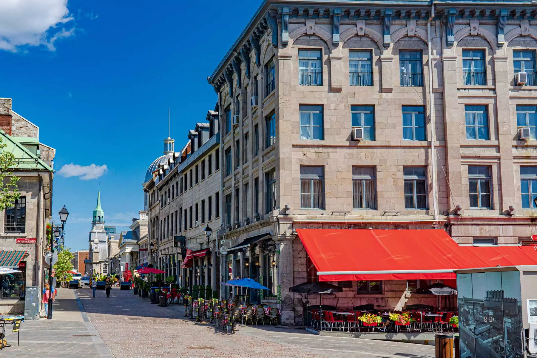 L'image montre une rue typique de la vieille ville bordée d'anciens bâtiments et de boutiques