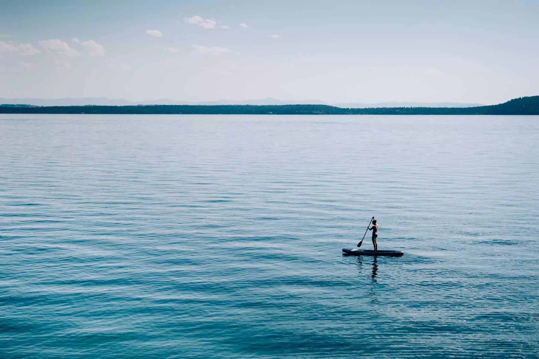 Kvinde står op padle boarder padler på Flathead Lake, Montana, USA