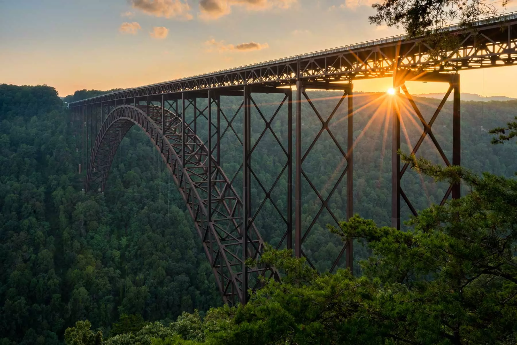 O sol ponse detrás das vigas da ponte de arco alto de New River Gorge en West Virginia