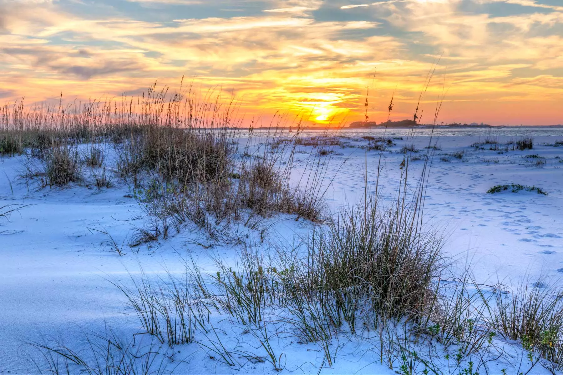 ဖလော်ရီဒါပြည်နယ်၊ Gulf Islands National Seashore ရှိ Fort Pickens ကမ်းခြေရှိ ပင်လယ်ကမ်းခြေများနှင့် သဲခုံများပေါ်တွင် ရောင်စုံနေဝင်ချိန်။