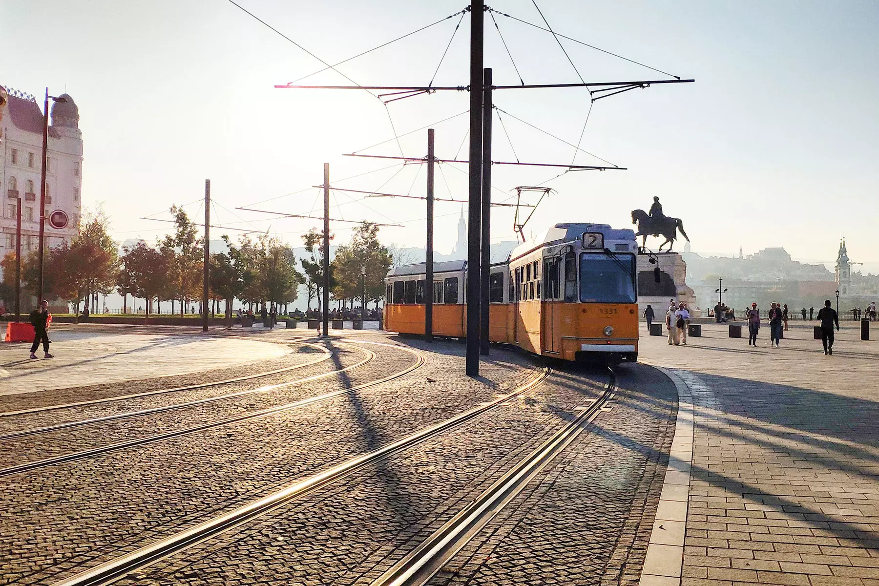 Tram Melyn nodweddiadol ar Lan yr Afon Danube ger adeilad Senedd Hwngari yn Budapest, Hwngari