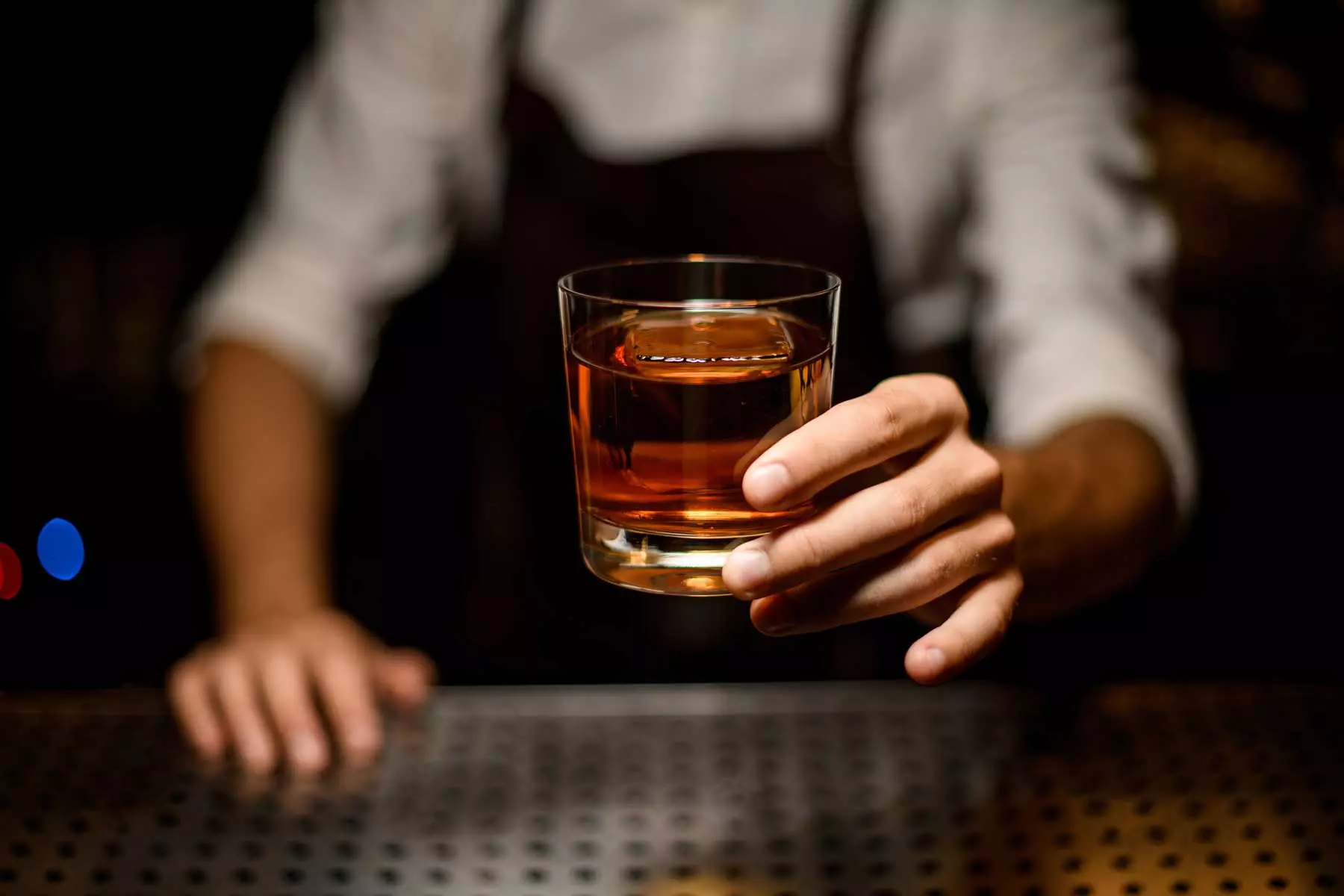 Bartender professjonali li jservi cocktail fil-ħġieġ b'kubu wieħed kbir tas-silġ