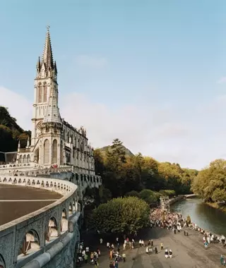 Touristen ausserhalb vum Sanctuary vun der Muttergottes vu Lourdes zu Lourdes, Frankräich