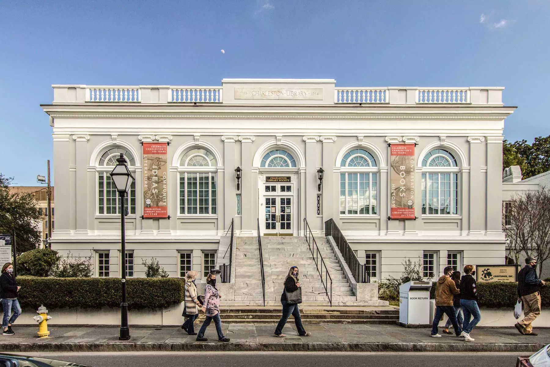 Exterior del edificio histórico de la Sociedad de la Biblioteca de Charleston mientras los peatones caminan delante