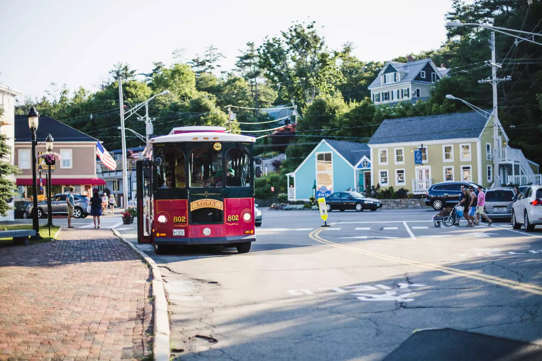 Doğu Coa'da güzel bir köy olan Ogunquit caddesinde eski bir otobüs, yürüyen insanlar ve arabalar.