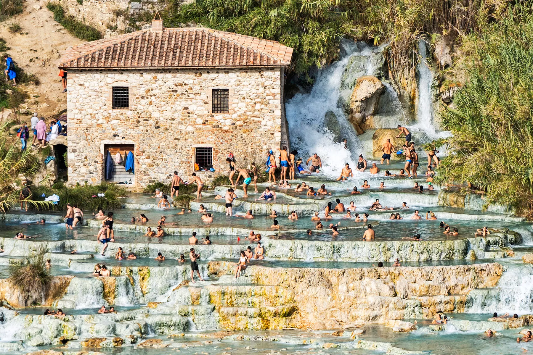 Mitmed inimesed kogunevad ja laiutavad end Toscanas Cascate del Mulino joa ja kuumaveeallikate, Saturnia thermae juures.