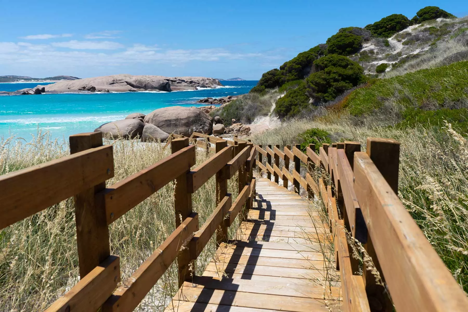 Foto de una pasarela de madera que conduce a la playa con un mar azul brillante, el Parque Nacional Cape Le Grand, Australia Occidental