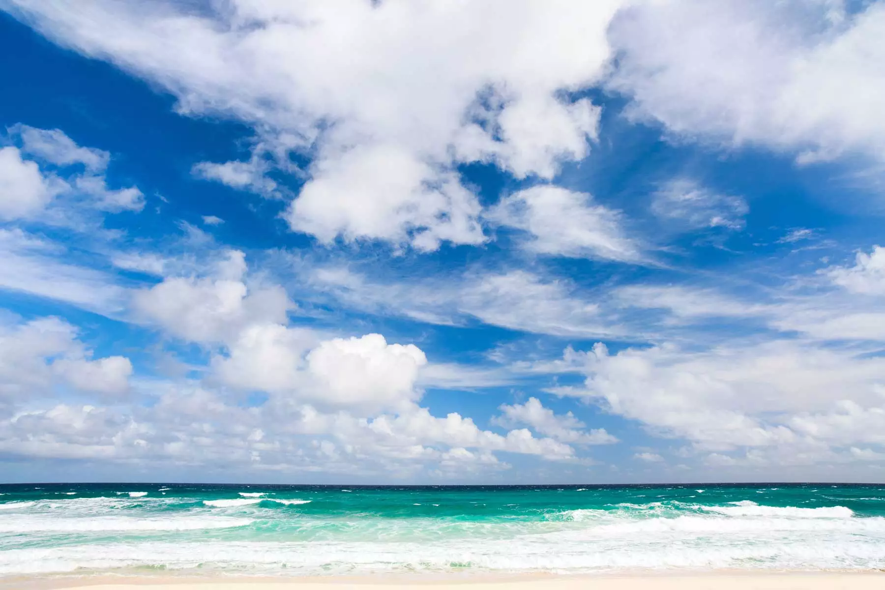 Nuvens brancas fofas, céu azul e água turquesa na Ilha Eleuthera, Bahamas