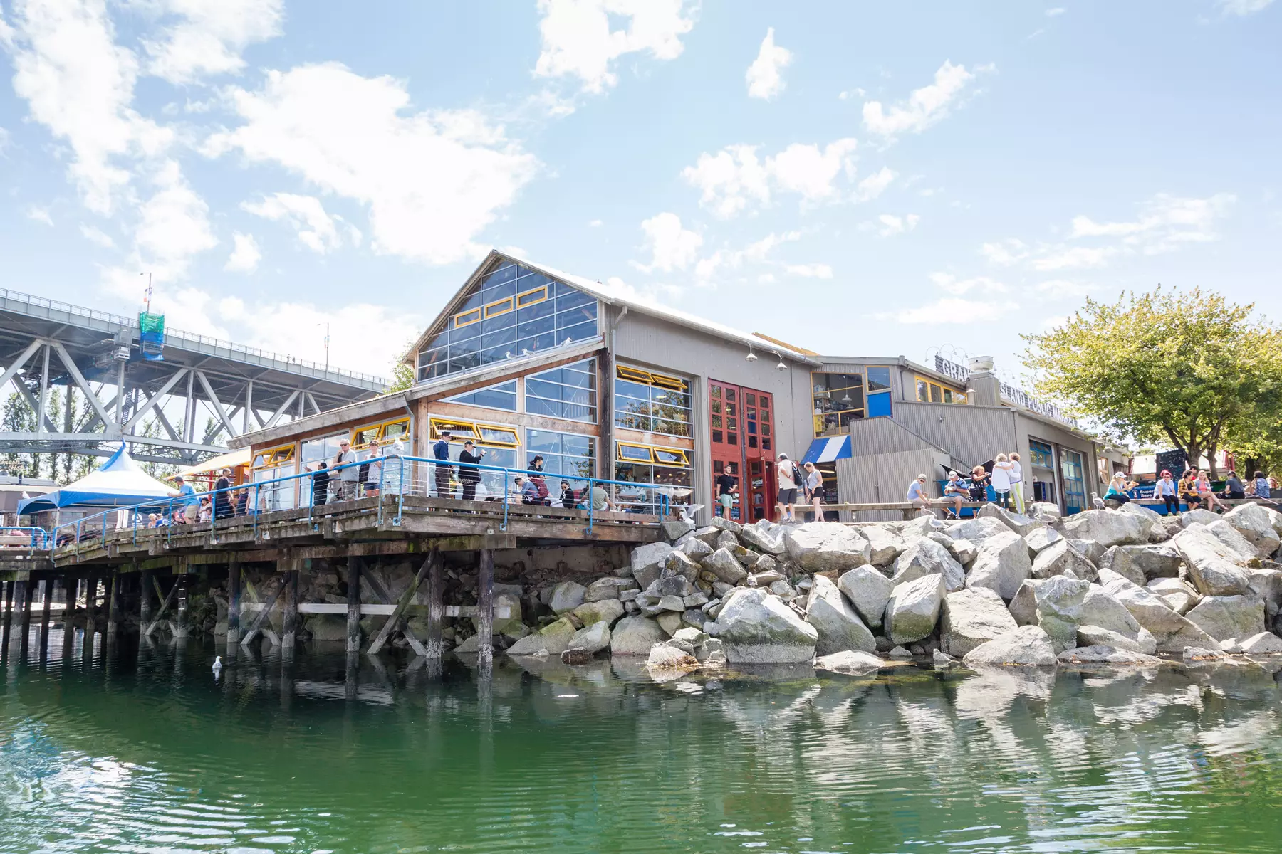 Besucher raschten um Granville Island Public Market zu Vancouver, Kanada. Et ass Heem fir iwwer 100 Ubidder déi frësch Meeresfrüchte, Fleesch a Spezialitéiten ubidden.