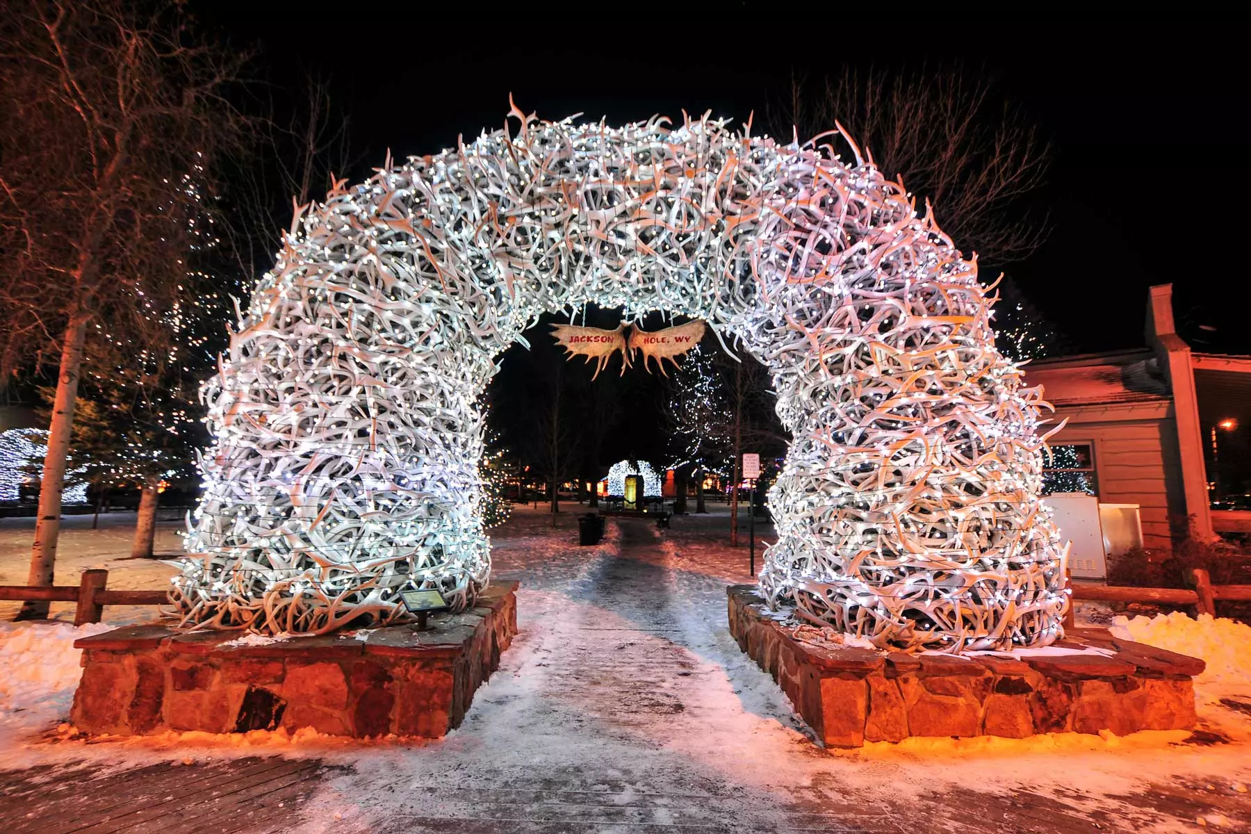 De grandes arches en bois de wapiti se courbent au-dessus des quatre entrées d'angle de la place de Jackson Hole. Les bois sont là depuis le début des années 1960, et de nouveaux arcs sont actuellement assemblés pour les remplacer. Illuminé la nuit pour Noël.